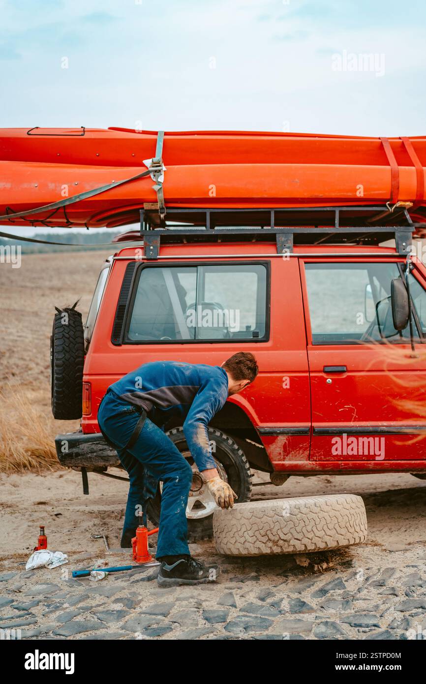 Man rolls a new replacement wheel to 4x4 off road truck Stock Photo - Alamy