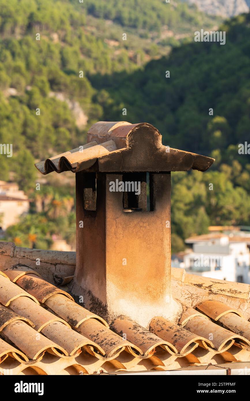 Traditional chimney rising above terracotta tiled roof of house in ...