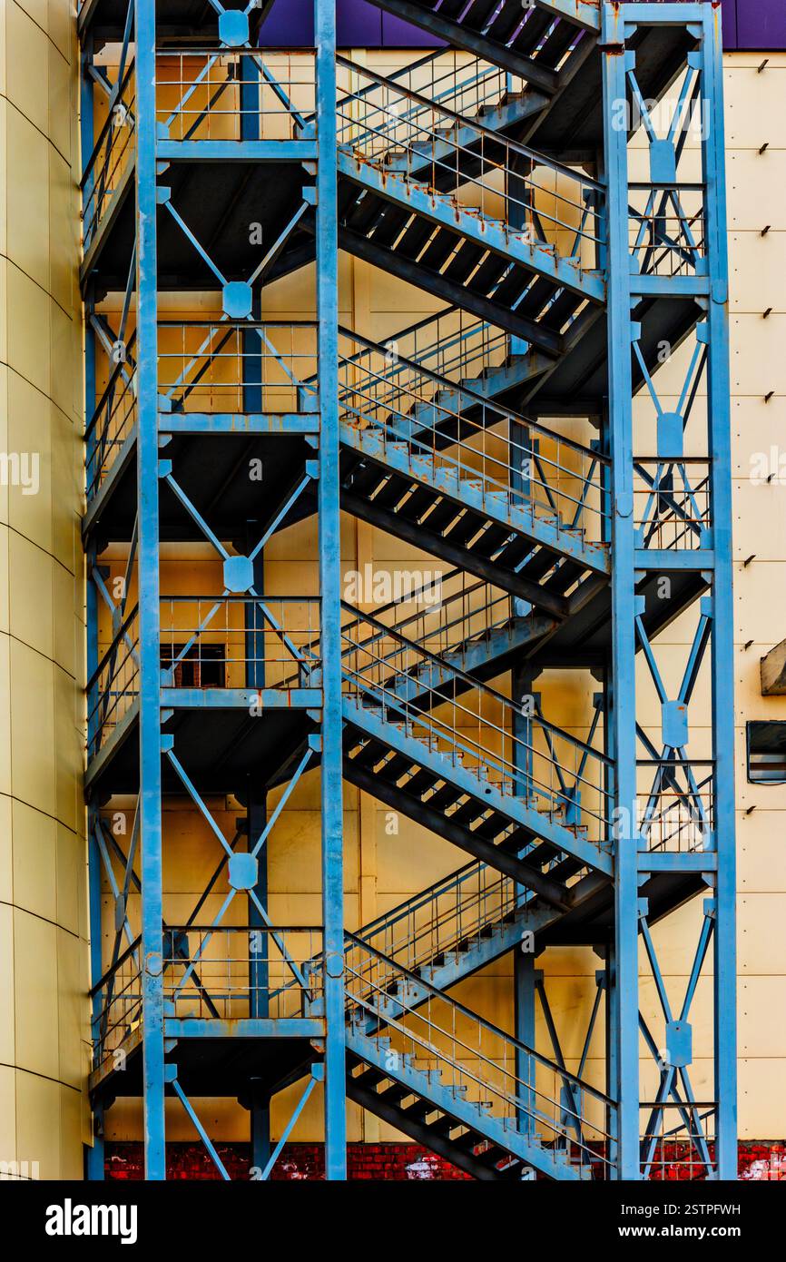 Tall fire escape made of metal painnted in blue color with spots of ...