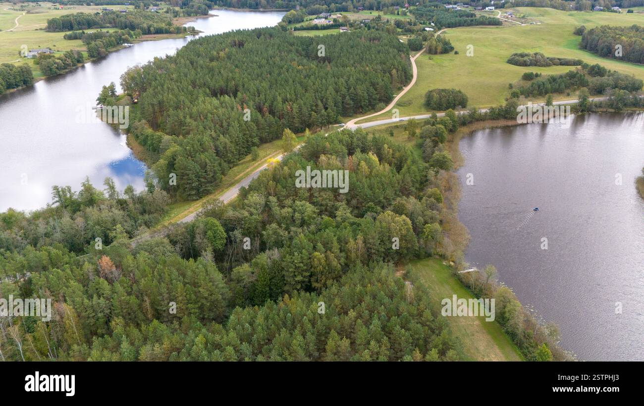 Aerial view of a lush green forest surrounded by two lakes, with a ...
