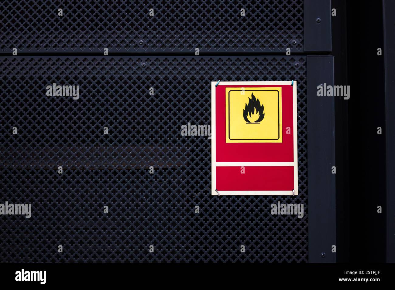 Cautionary fire warning sign attached to a black metallic grill, close ...