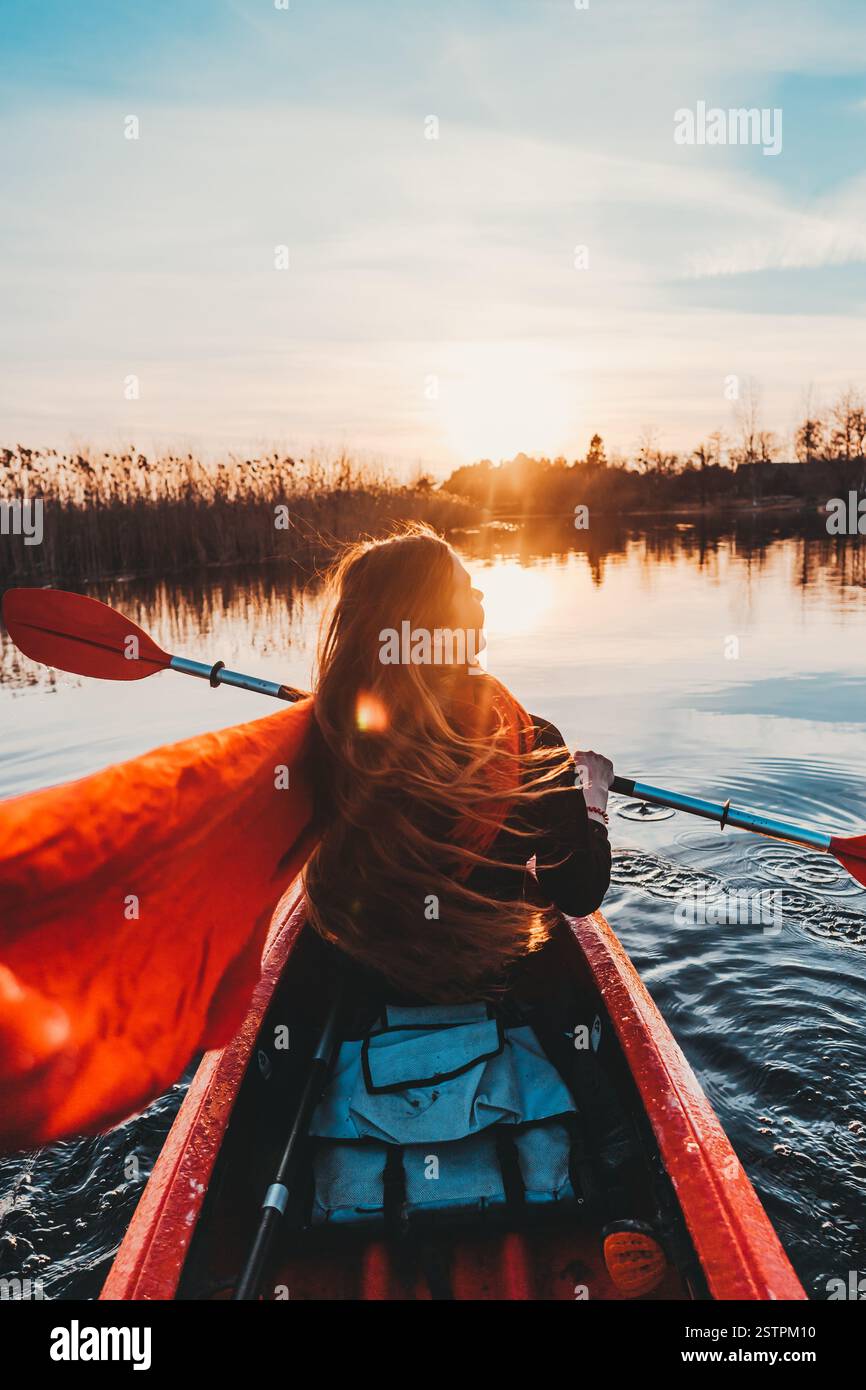 Back view of happy cute girl holding paddle in a kayak on the river ...