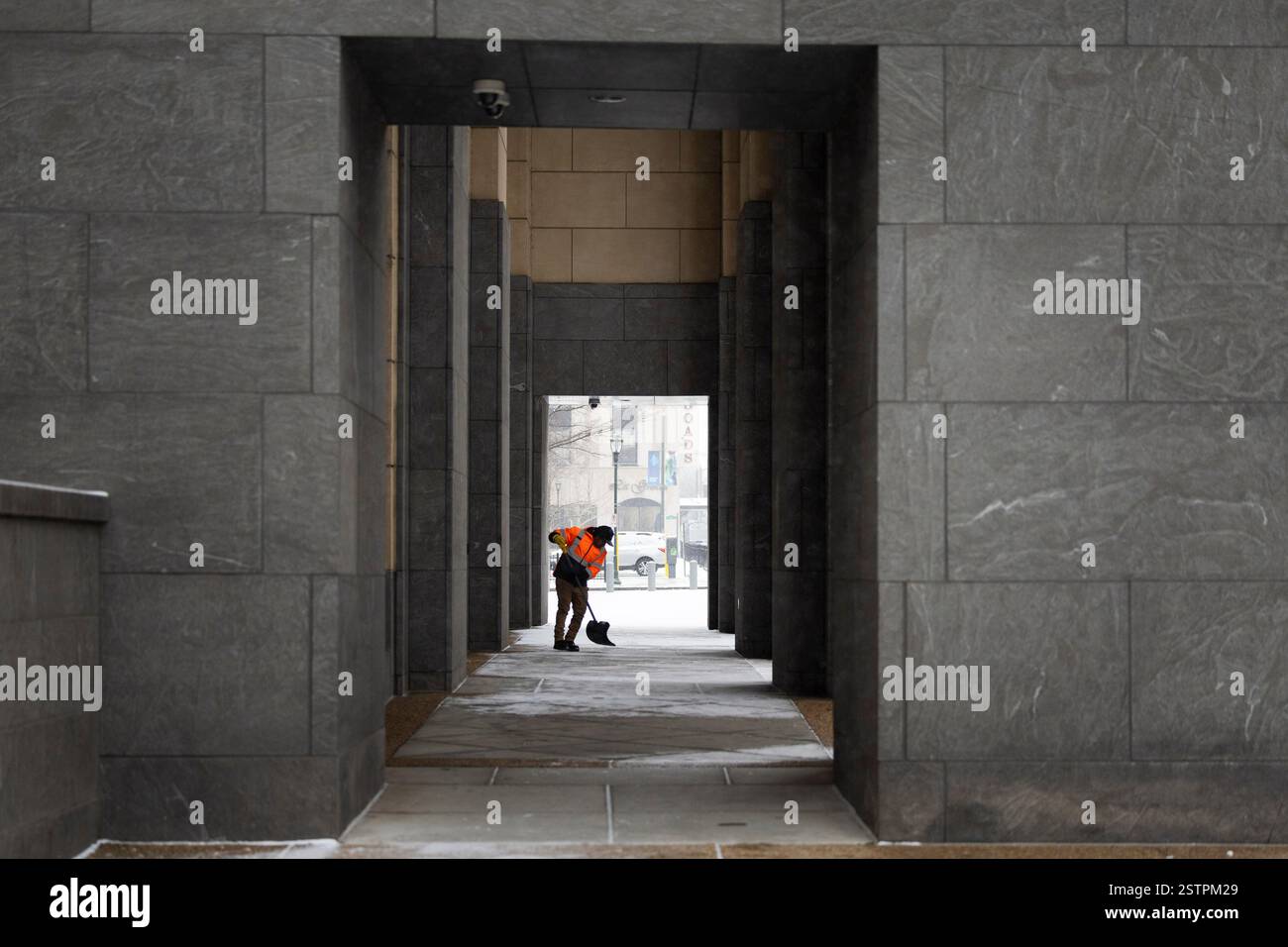 A person shovels snow on the sidewalk of East Broad St. in Richmond, Va ...