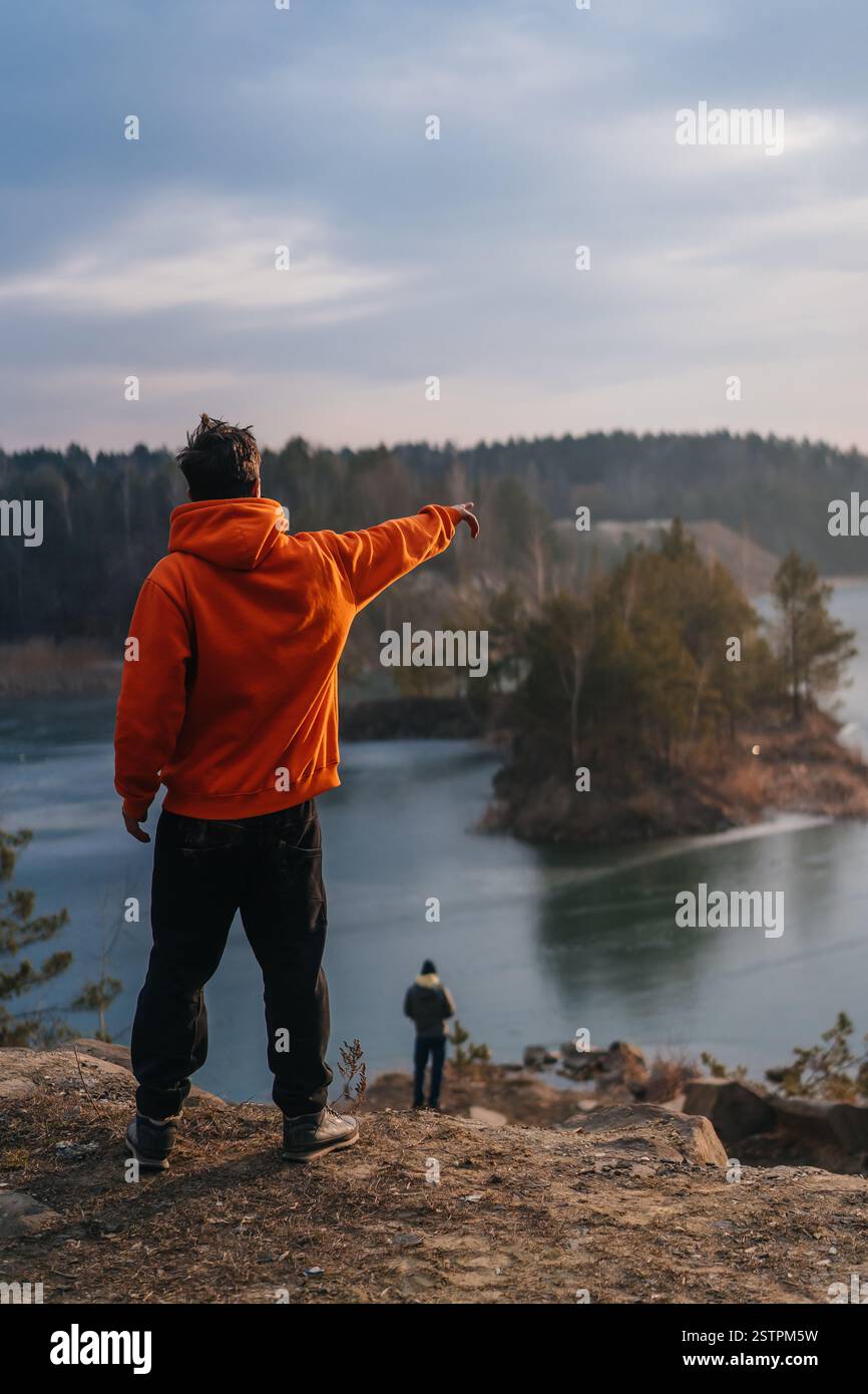 A young man standing on the edge of a cliff poses for the camera Stock ...