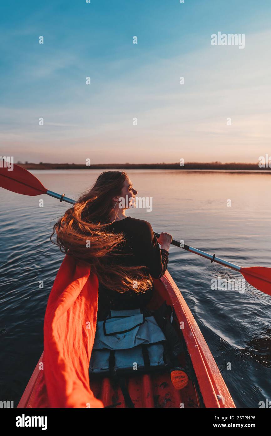 Back view of happy cute girl holding paddle in a kayak on the river ...