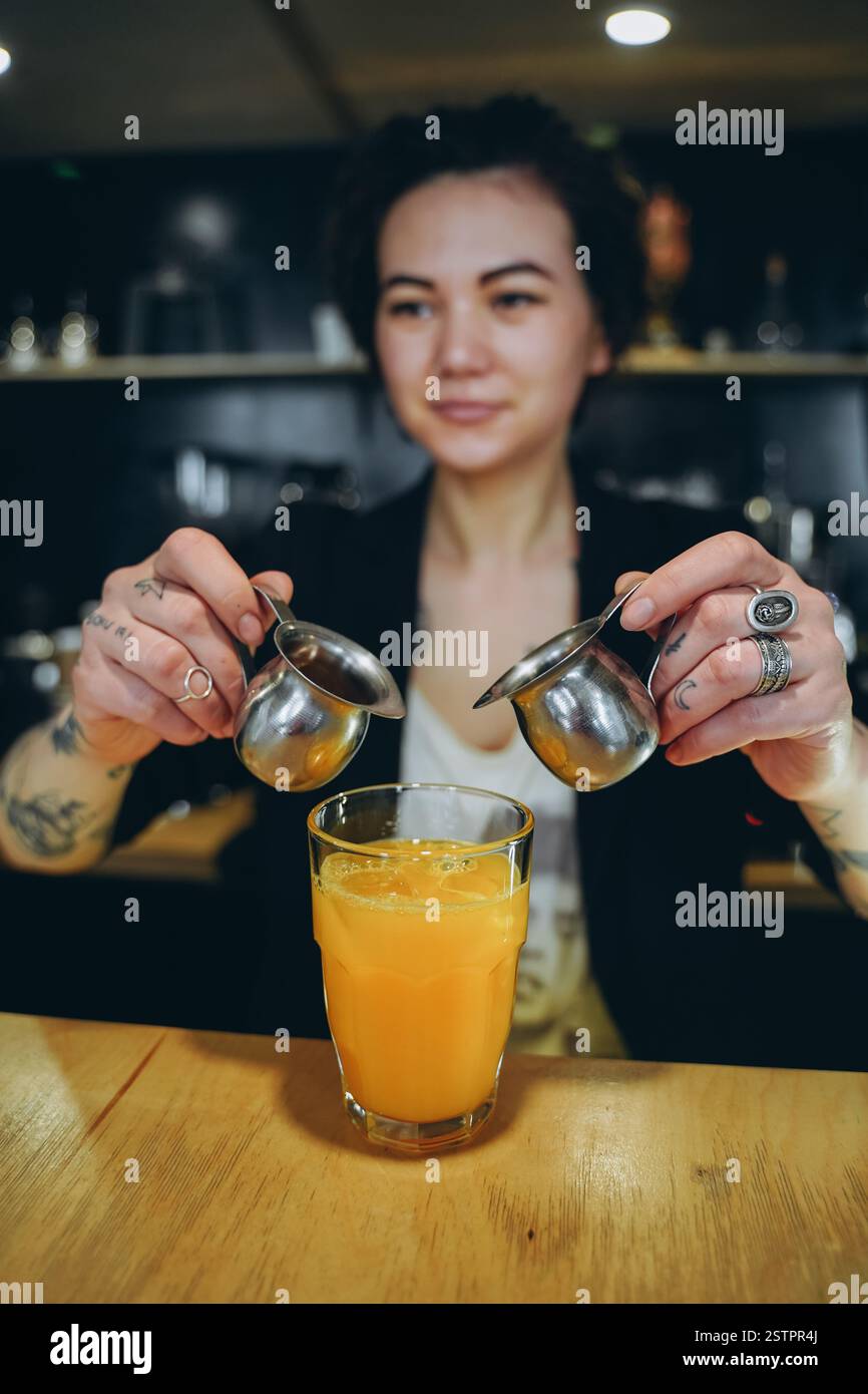 KIEV, UKRAINE - APRIL 14, 2019 A girl makes a orange coffee cocktail ...