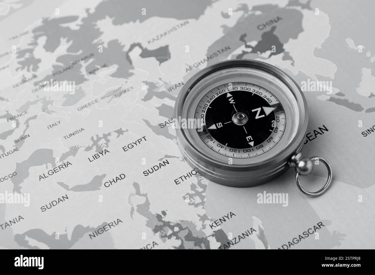 Compass on world map, toned in black-and-white Stock Photo - Alamy