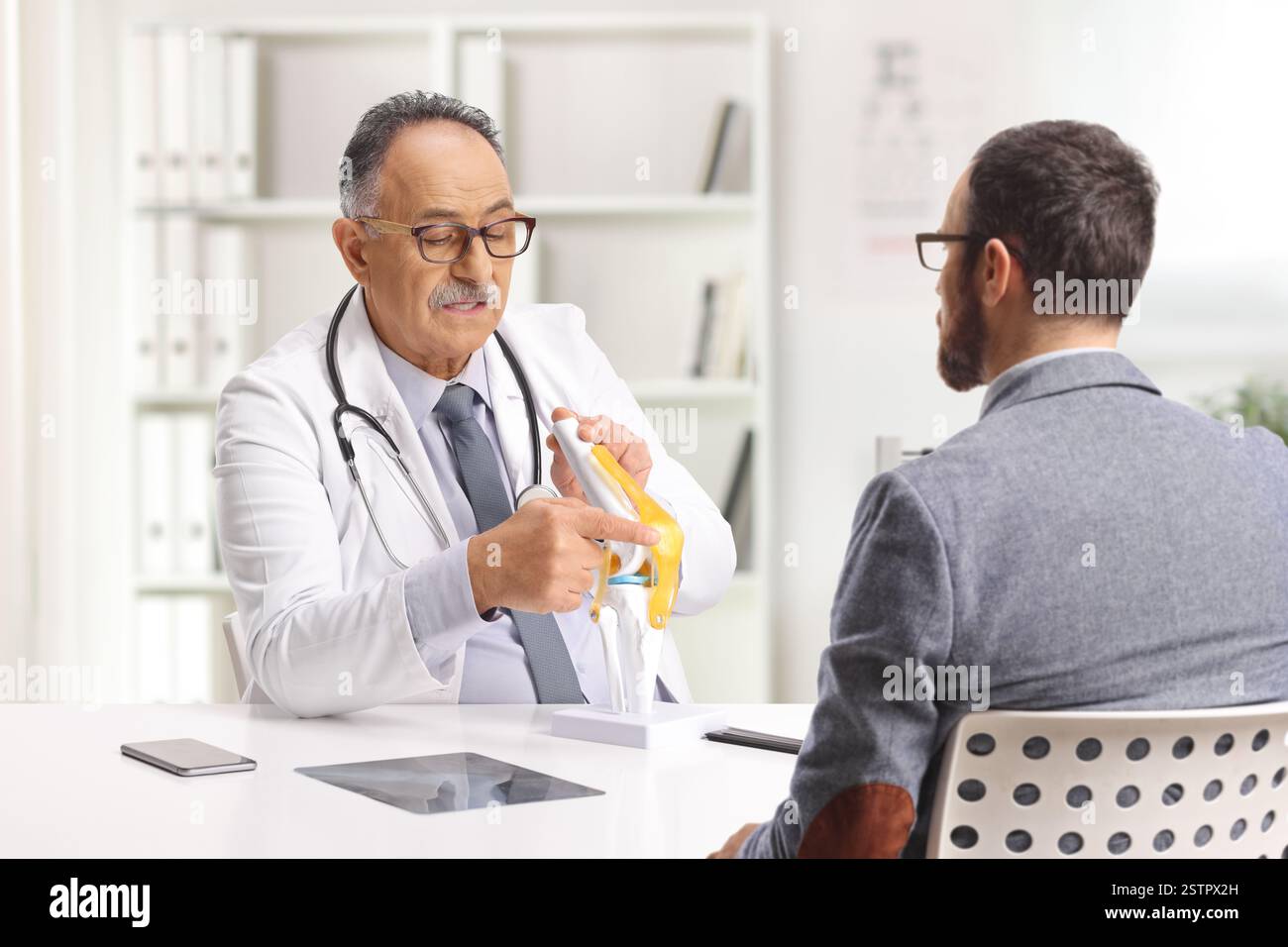 Doctor explaining a knee surgery procedure to a male patient in a ...
