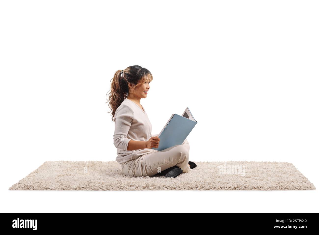 Young asian woman sitting on a carpet and reading a book isolated on ...