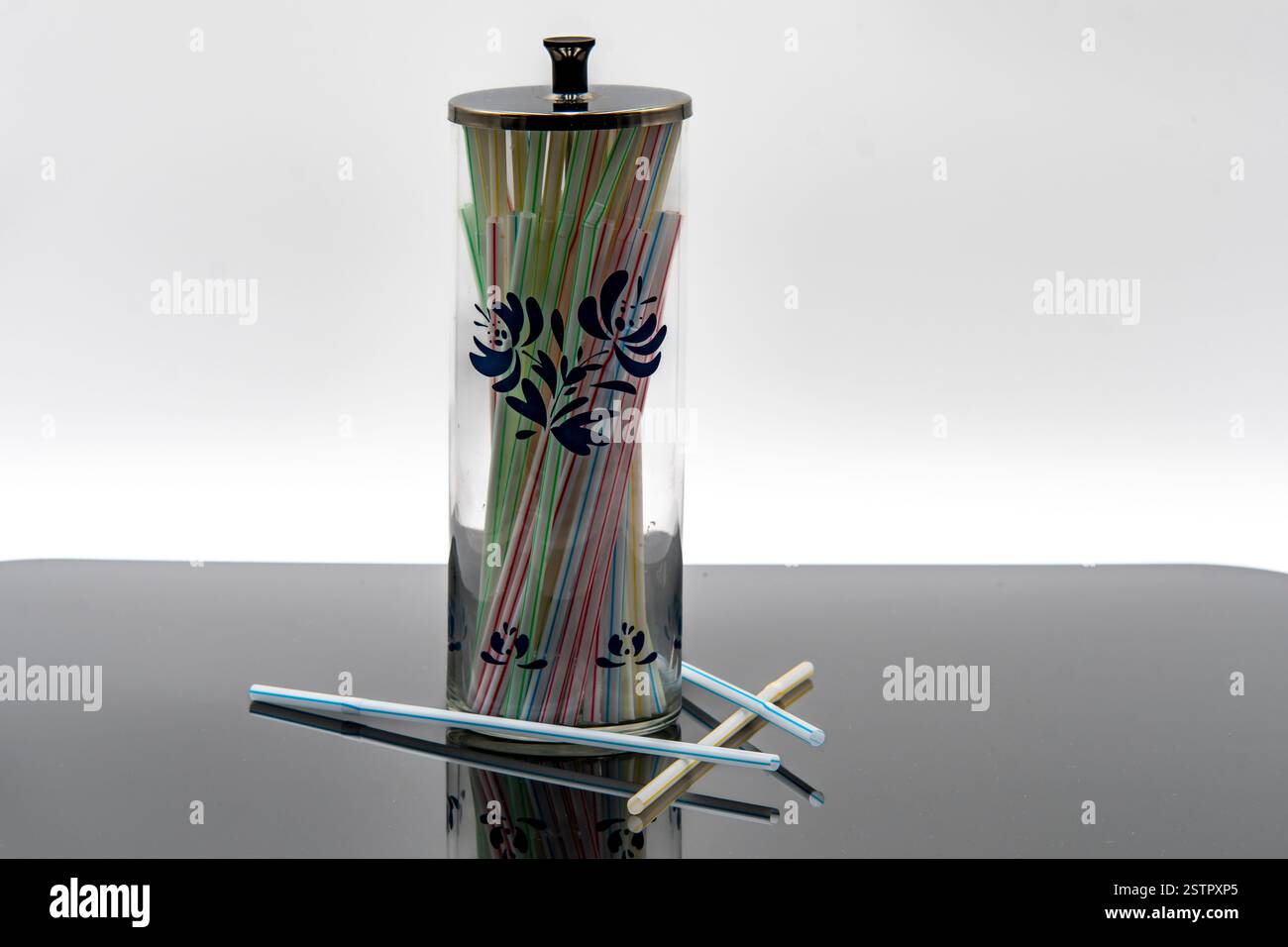 A transparent cylindrical container holds various colorful plastic ...