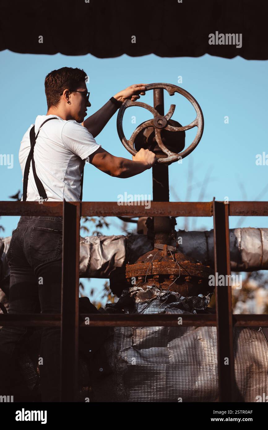 Guy in a shirt with suspenders turns the old valve Stock Photo - Alamy