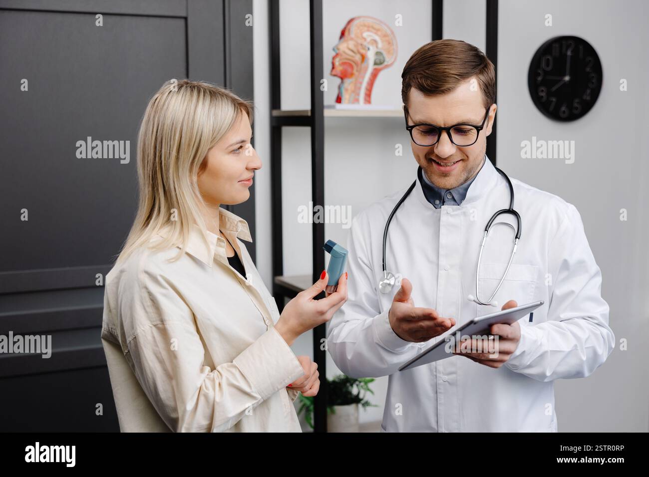 Male doctor holding in hand an aerosol inhaler on a demonstration to a ...