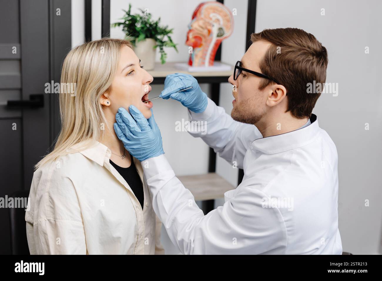 Doctor using inspection spatula to examine patient throat. ENT doctor ...