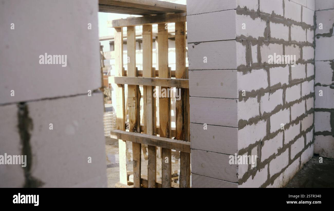 Construction workers build walls with white bricks under a sunny sky ...