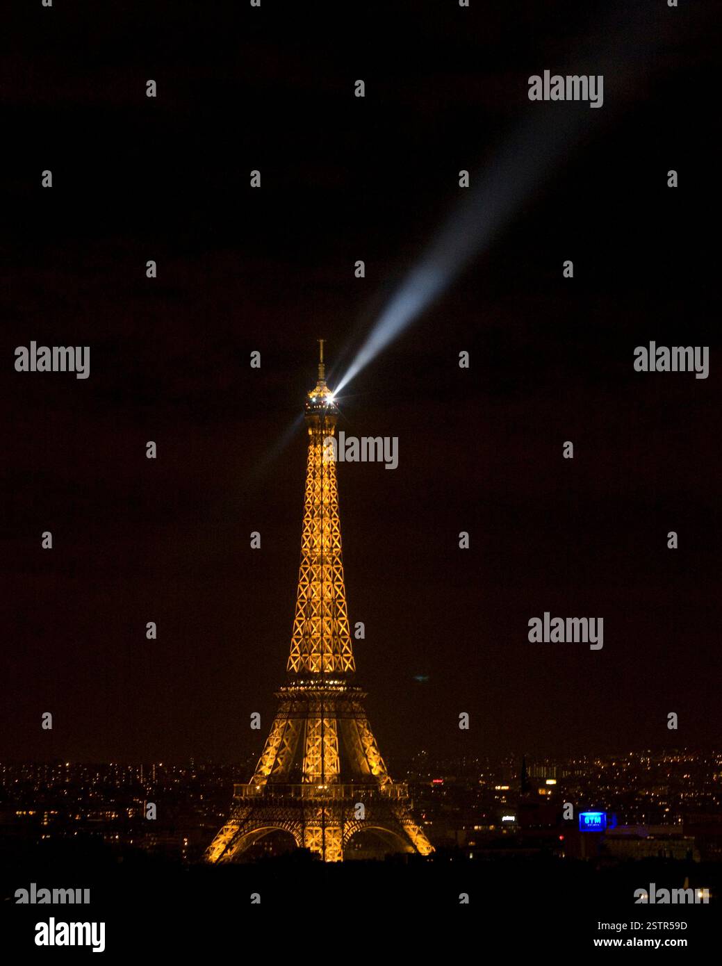 Night view of the Eiffel Tower with its golden lights and upward beam. Illuminated landmark ...