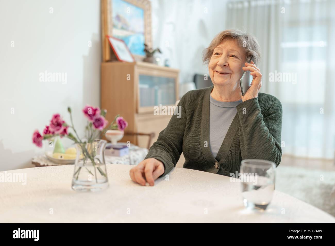 Elderly woman talking on a mobile phone at home. Concept of ...