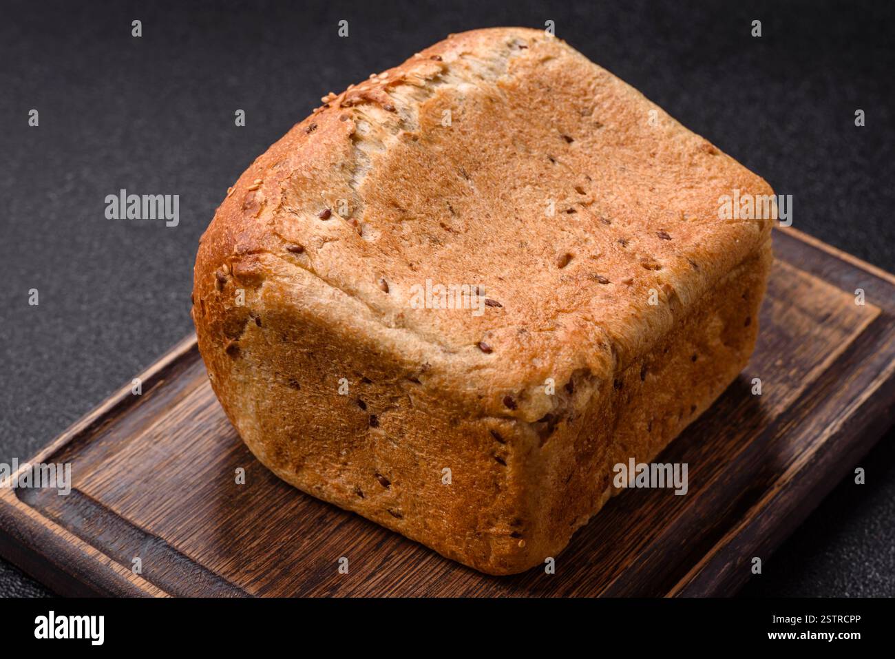 Brown bread with grains and seeds on a dark concrete background Stock ...