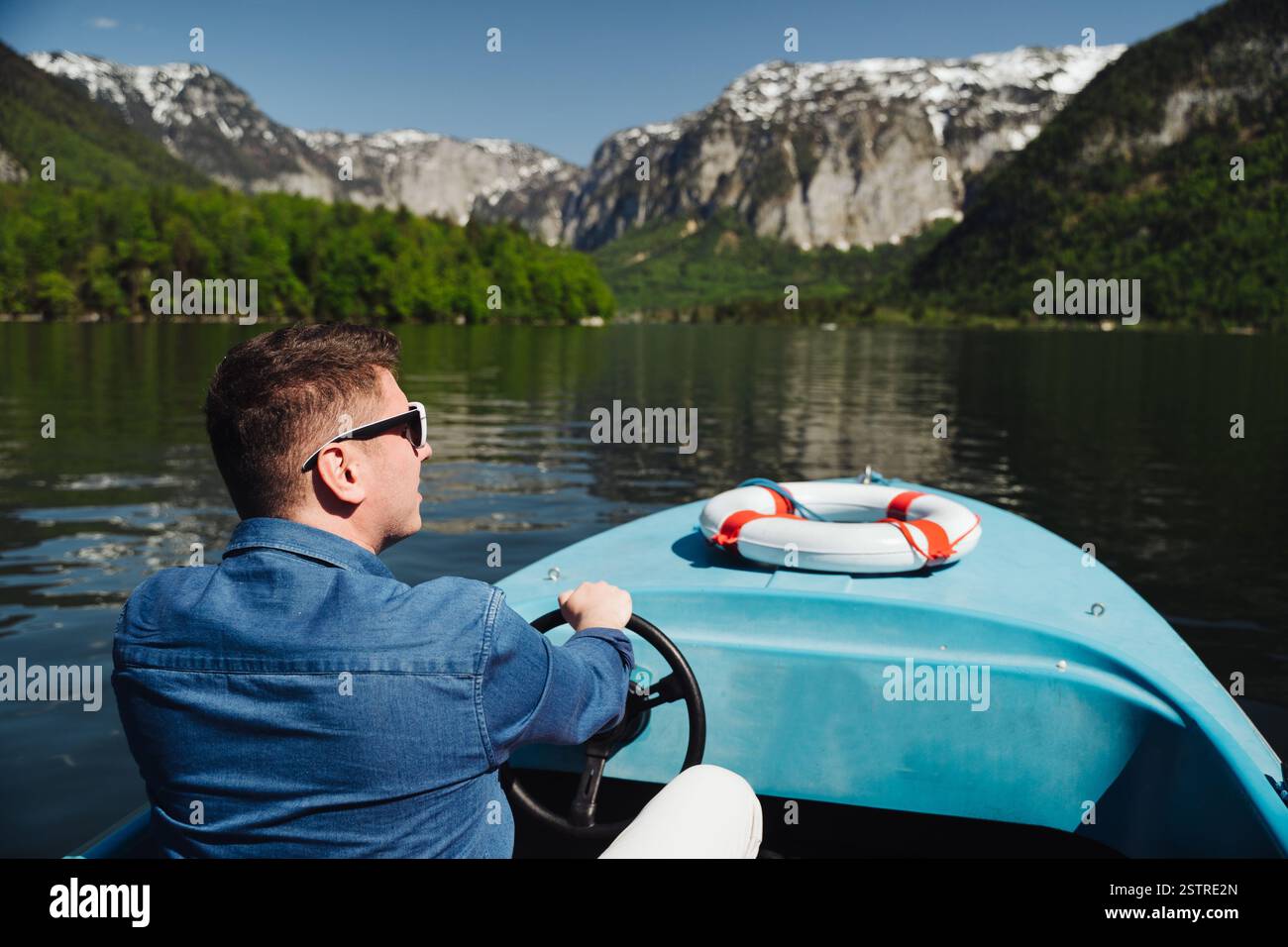 Handsome young guy controls a motorboat on a mountain lake Stock Photo ...