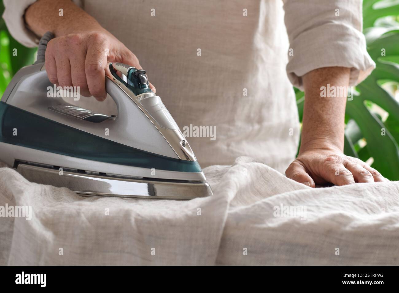 Woman ironing linen fabric with electric iron Stock Photo - Alamy