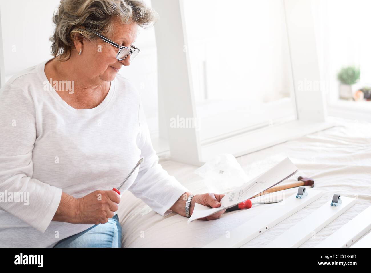Senior woman reading a manual to assemble furniture Stock Photo - Alamy