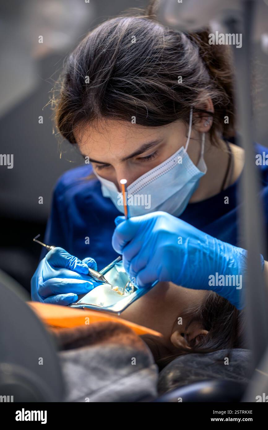 The dentist treats the child's tooth using a rubber dam. Close-up of ...