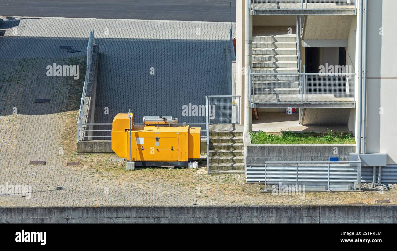 Big yellow electric power generator behind building hi-res stock ...