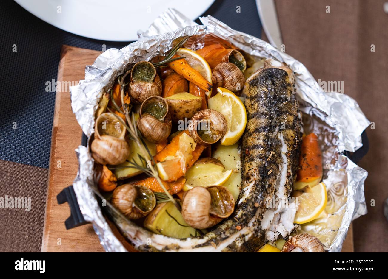 Grilled fish, sea snails with lemon and vegetables Stock Photo - Alamy