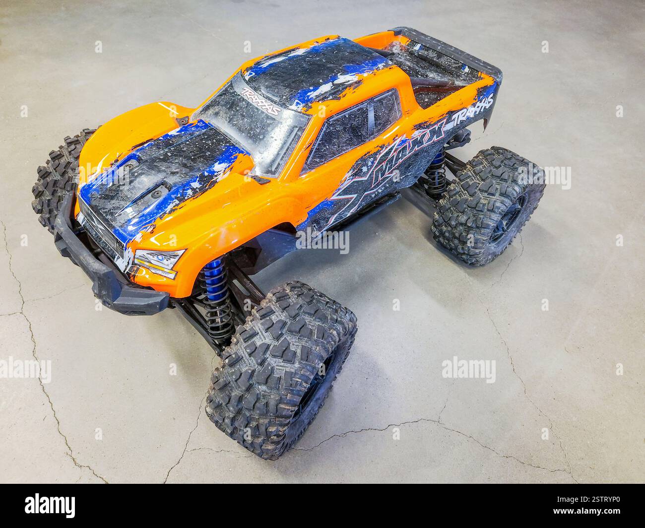 Traxxas X-Maxx remote-controlled truck with scratched orange body and ...