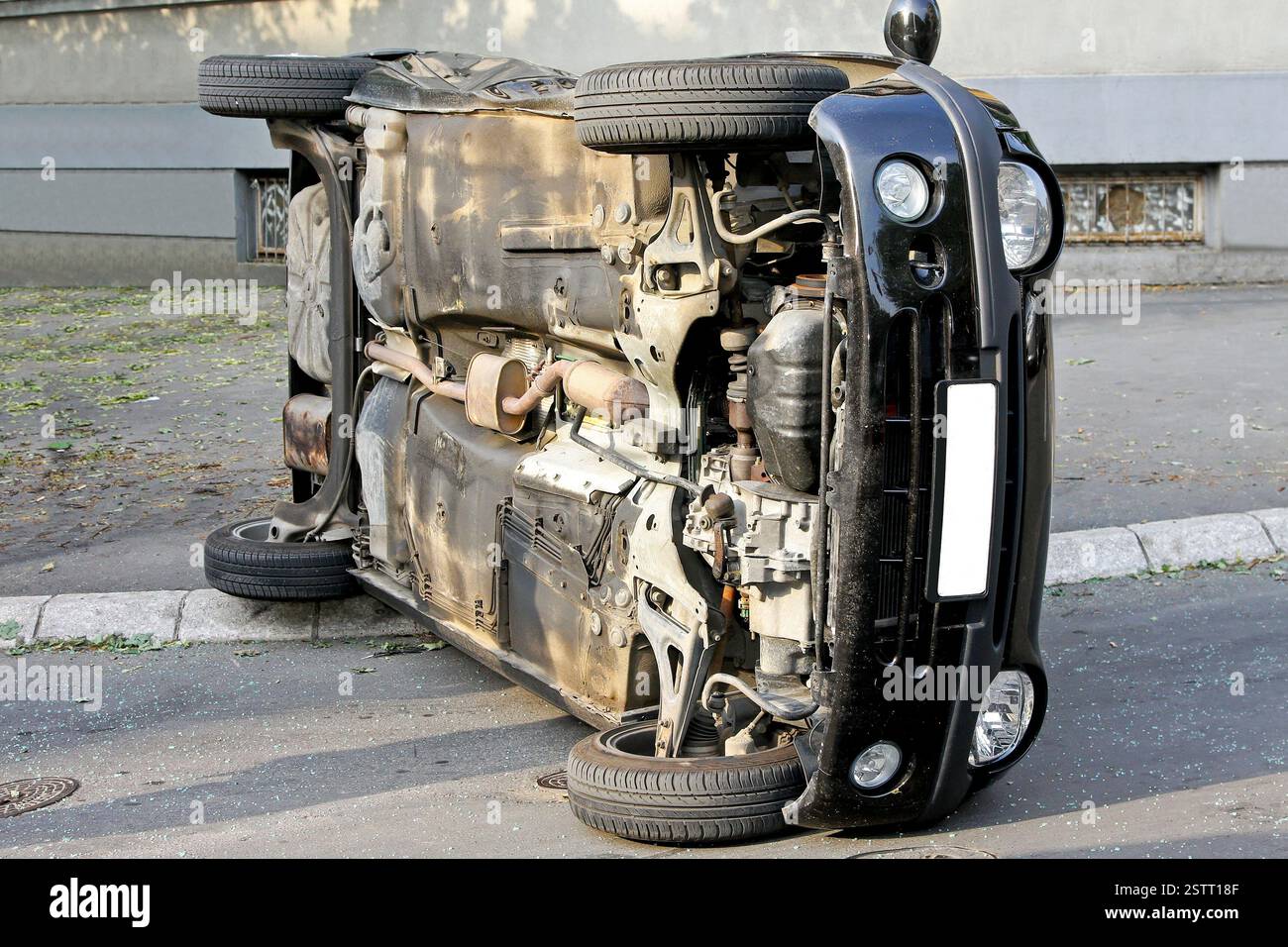 Small black car crashed and roll over side Stock Photo - Alamy