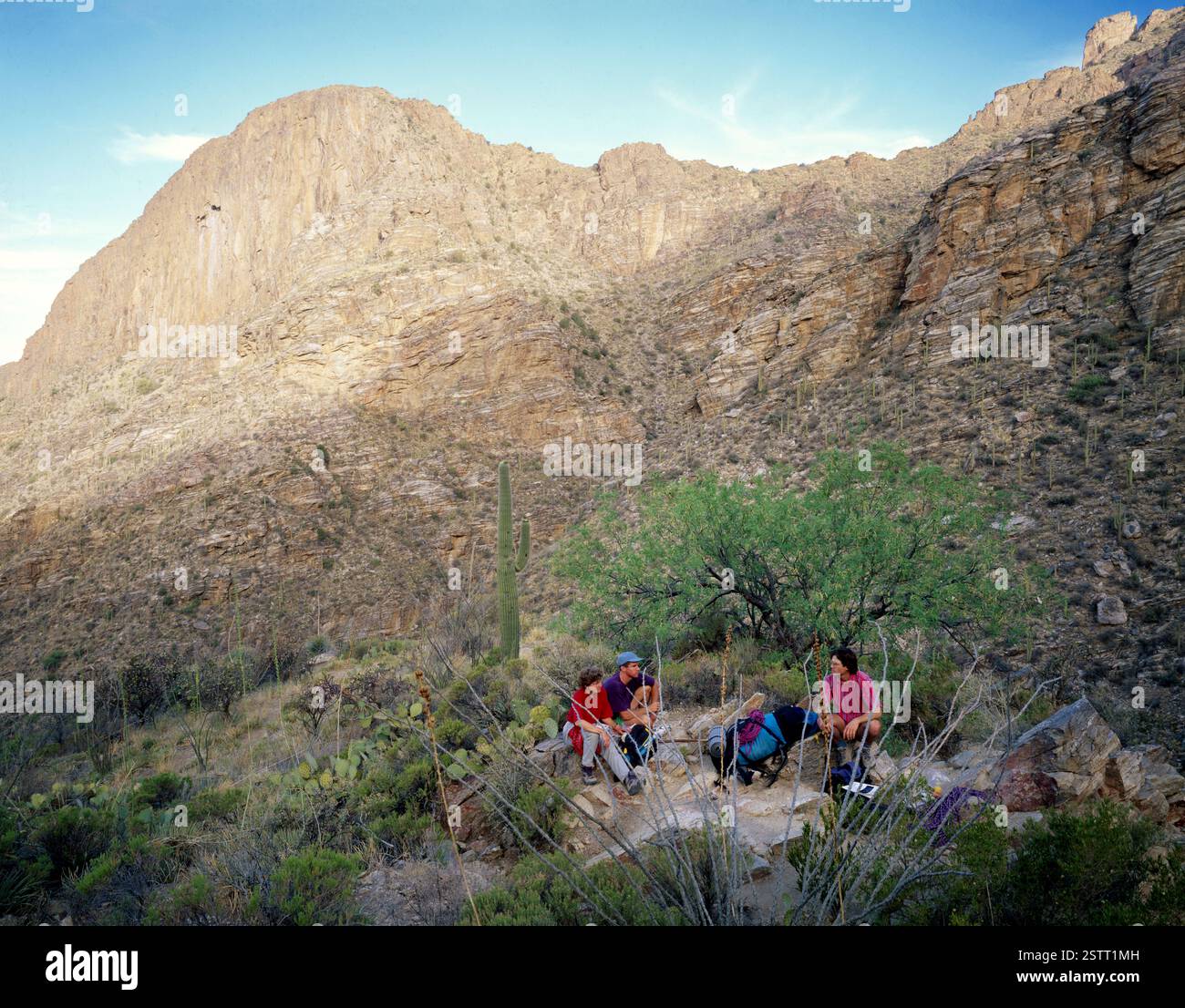 A small group of rock climbers rest on the trail to Finger Rock spire ...