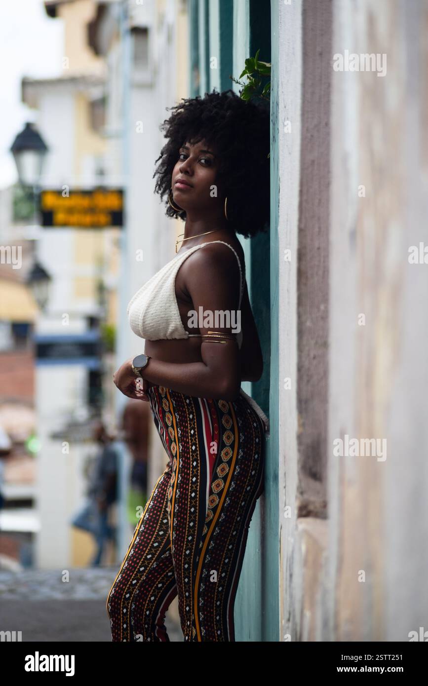Half-length photo of beautiful black woman with her back to an old wall ...