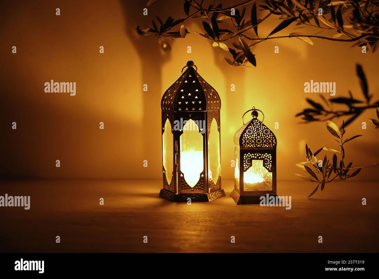 Two Moroccan lanterns on table at nigh. Blurred olive tree branches ...