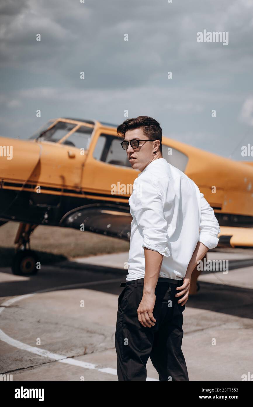 A man standing on the background of a small single engine plane. Runway ...