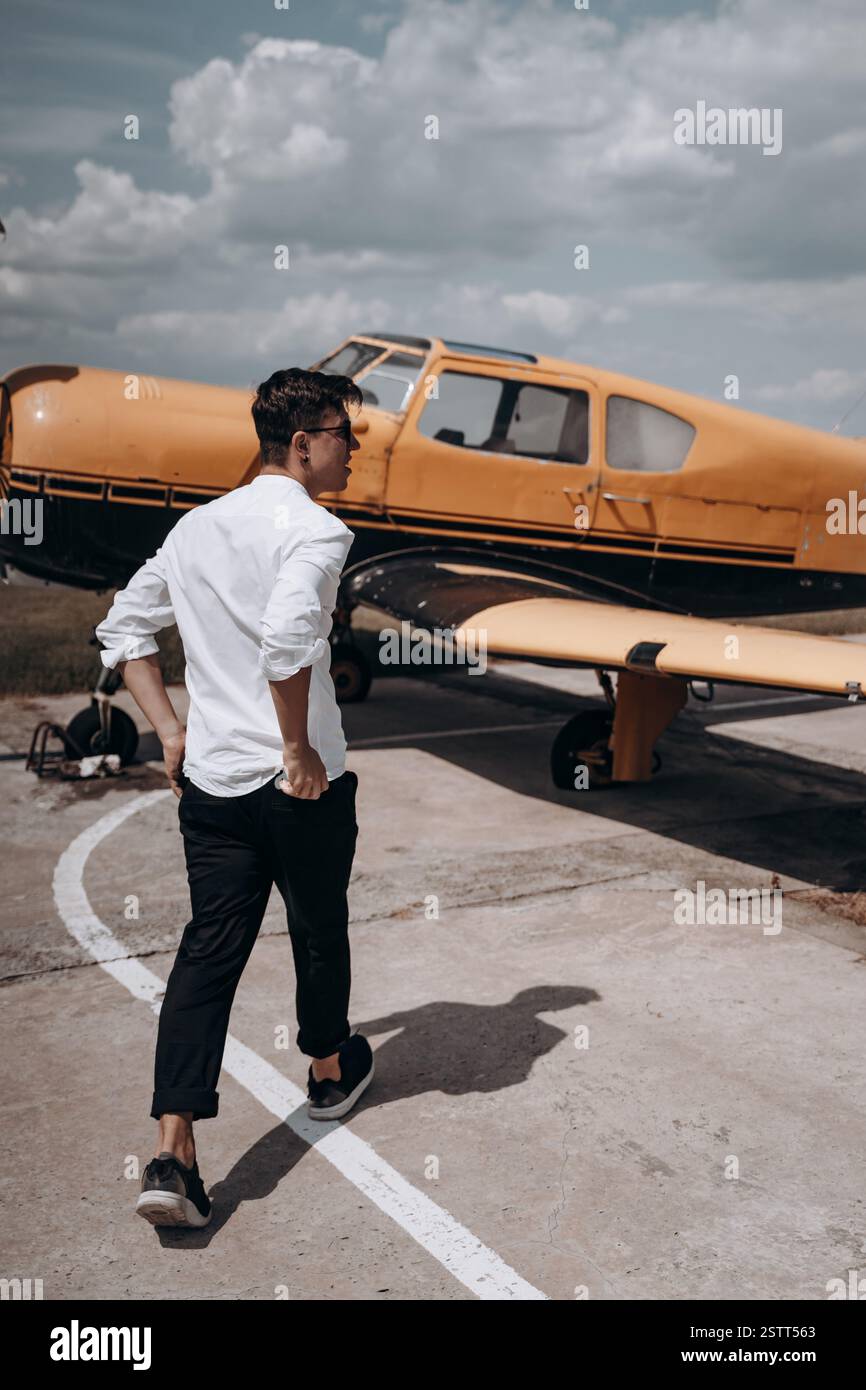A man standing on the background of a small single engine plane. Runway ...