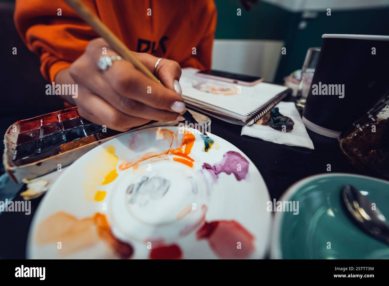 Close up of artist with palette, paint brush and easel painting at ...