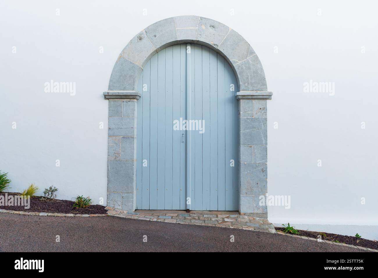 Light blue arched door with stone frame and white wall hi-res stock ...