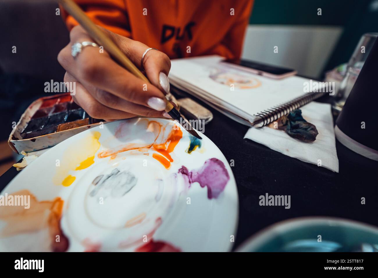 Close up of artist with palette, paint brush and easel painting at ...