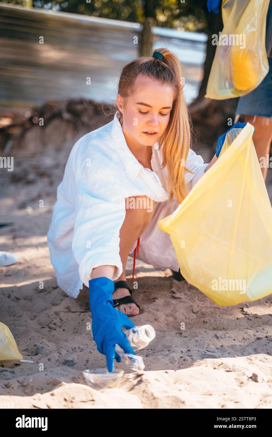 Girl picking up trash from the park. She collecting the litter in ...