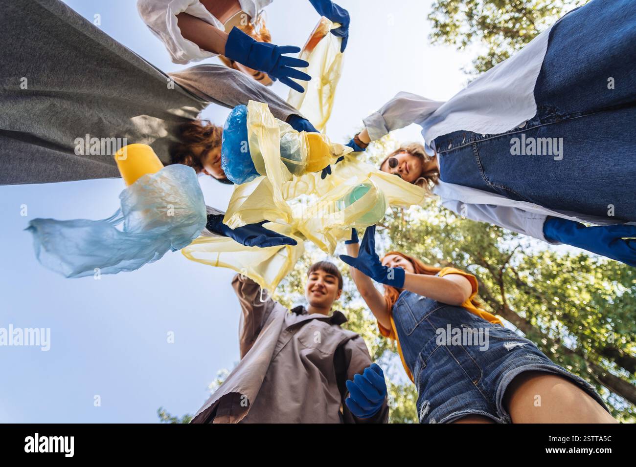 Group of activists friends throw a lot of garbage in a bag. Bottom-up ...