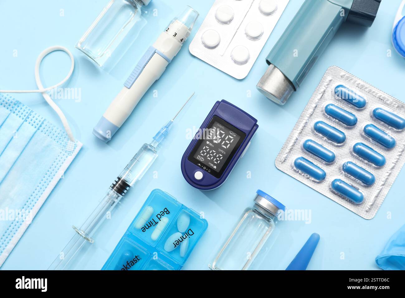 Composition with pulse oximeter, inhaler, syringe and medicines on blue ...
