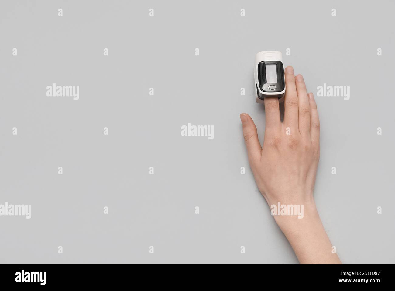 Female hand with pulse oximeter on grey background Stock Photo - Alamy