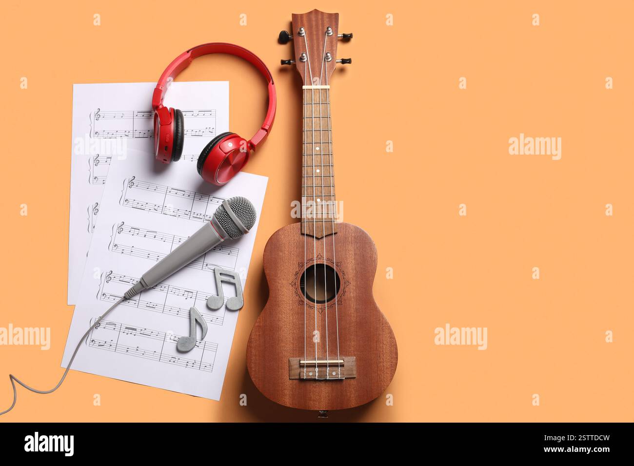 Ukulele, music sheets, microphone and headphones on color background ...
