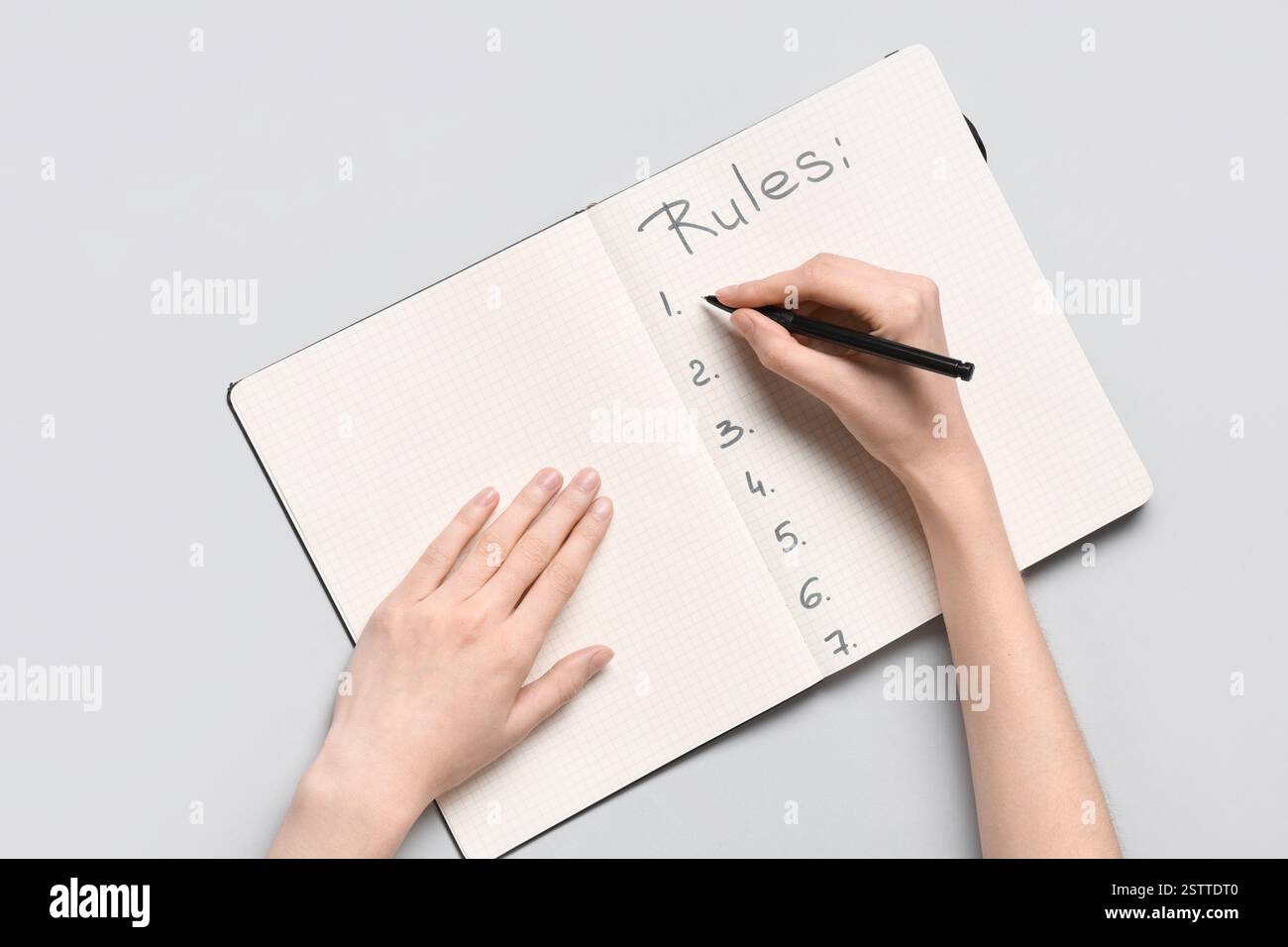 Woman writing list of rules in notebook on light background Stock Photo ...