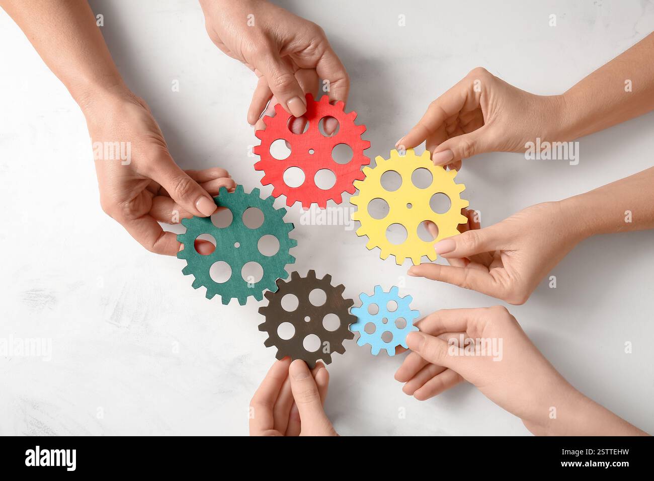 Hands holding wooden gears on light background, top view Stock Photo ...