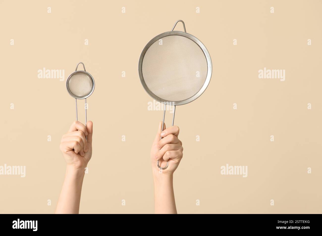 Female hands with sieves on beige background Stock Photo - Alamy