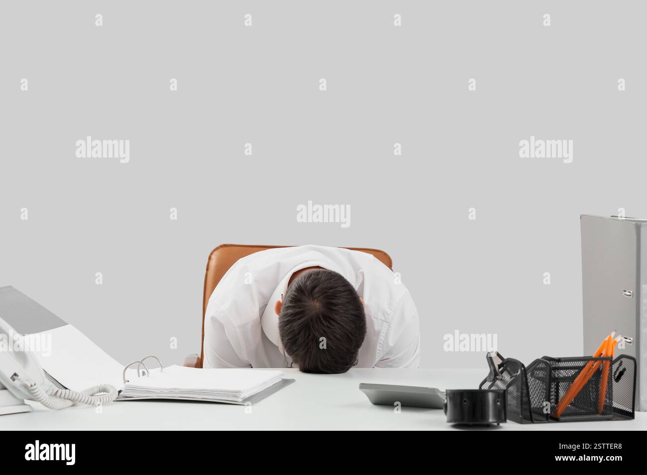 Tired male office worker at table on light background Stock Photo - Alamy