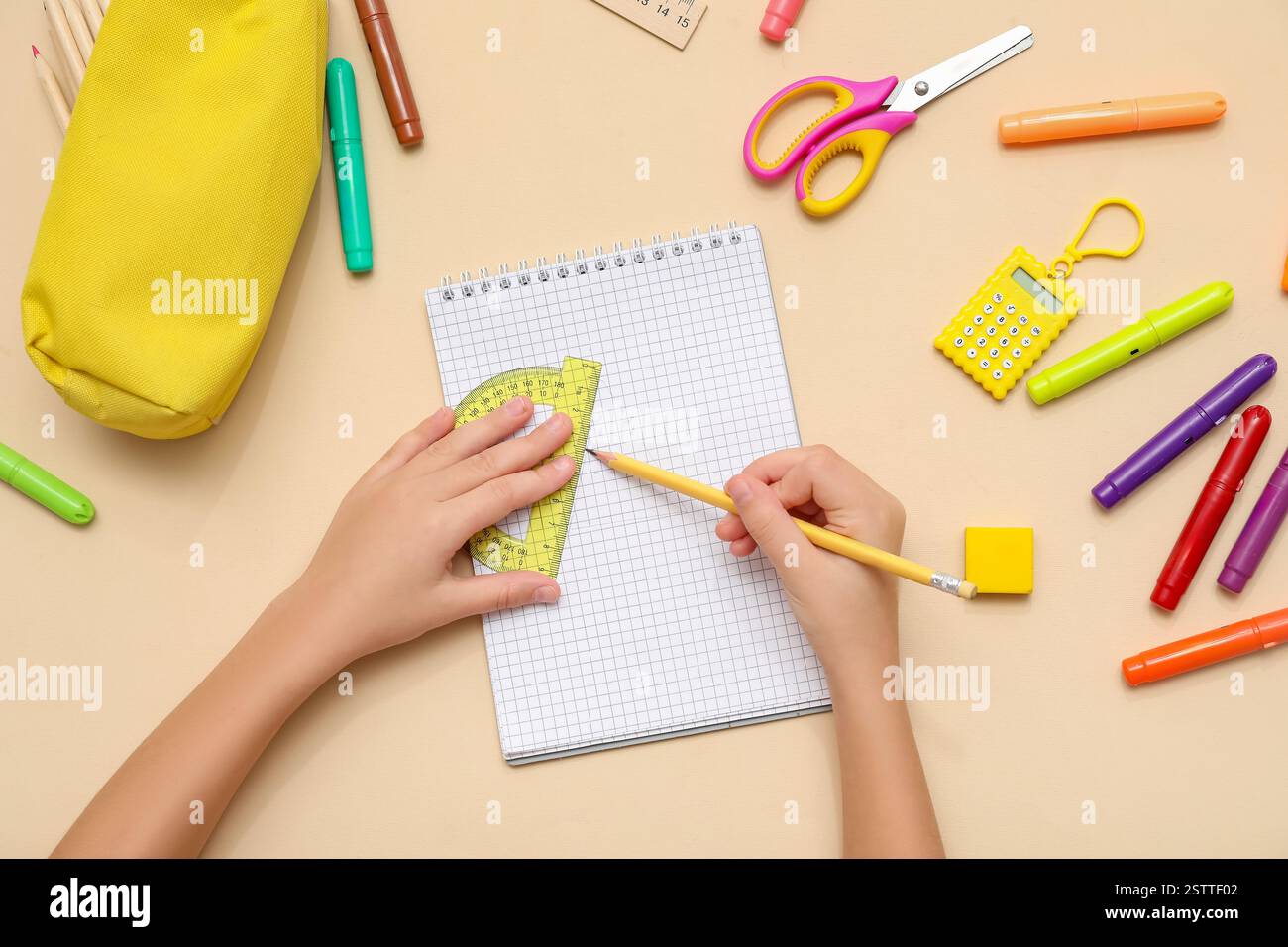 Child's hands drawing with protractor in notebook on beige background ...