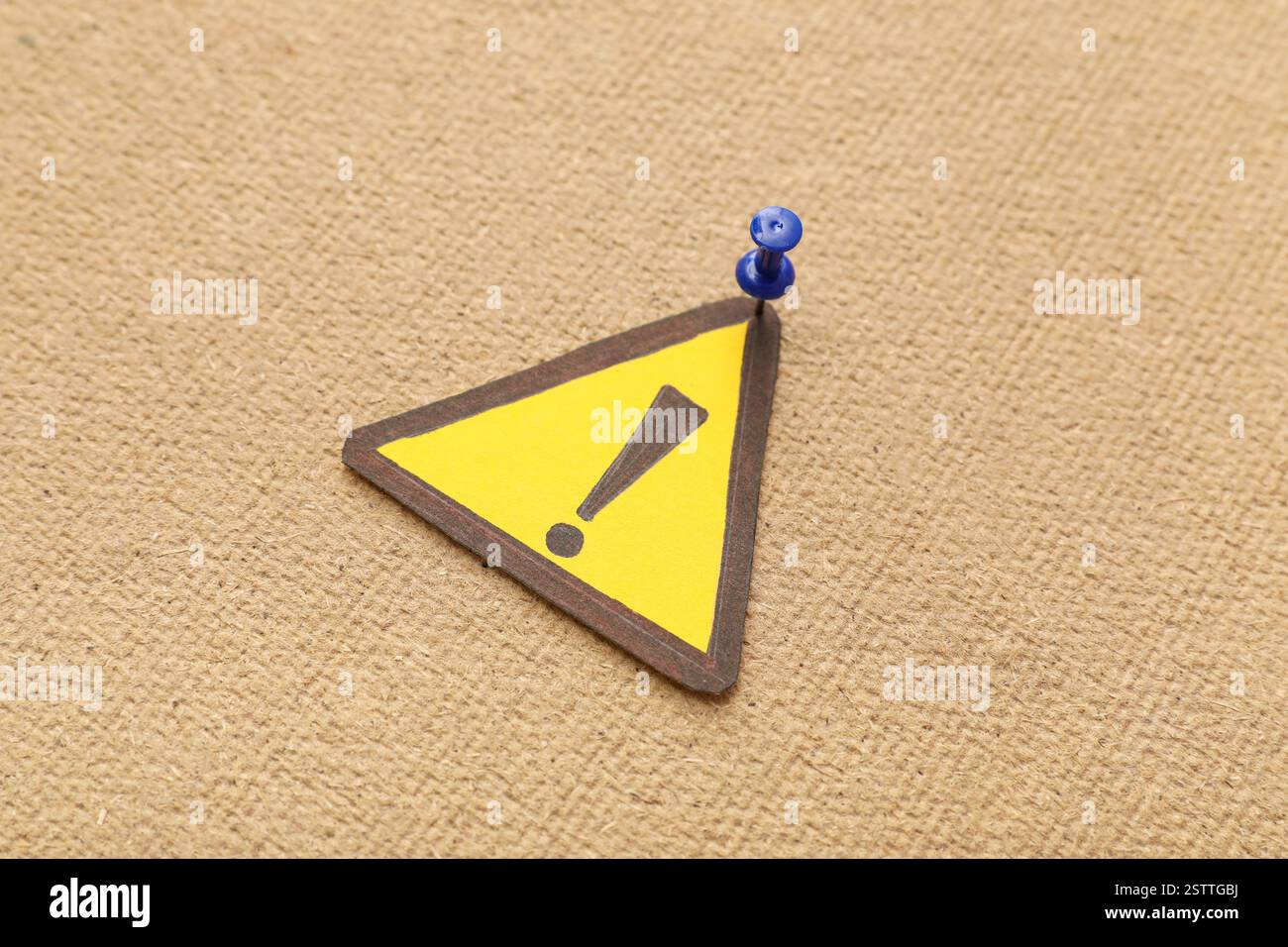 Yellow triangle with exclamation mark pinned on board Stock Photo - Alamy