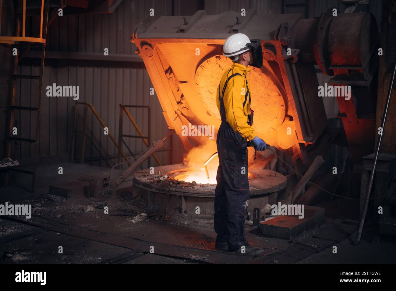 Worker monitors molten metal in an industrial furnace Stock Photo - Alamy
