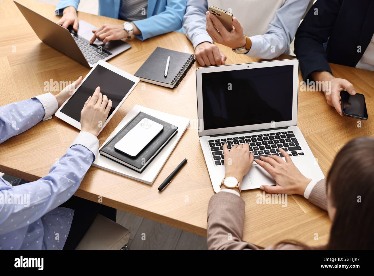 Group of people using different gadgets at wooden table in office ...